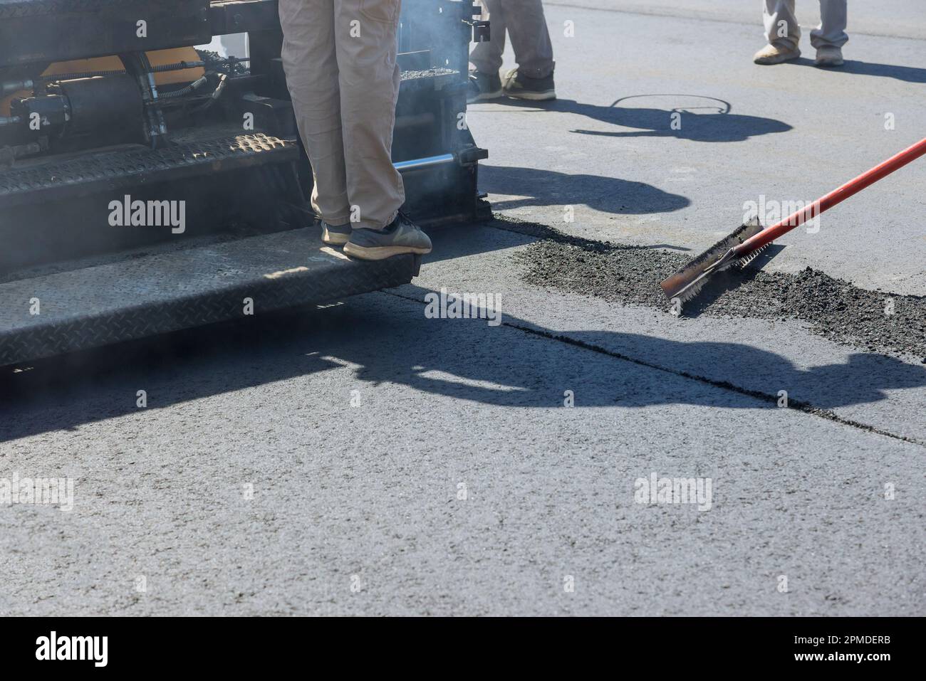 Pavement work is being carried out with asphalt being laid black gravel ...
