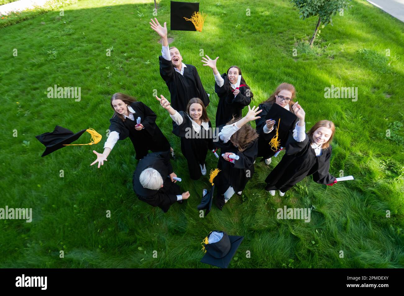 Classmates in graduation gowns throw their caps. View from above Stock ...
