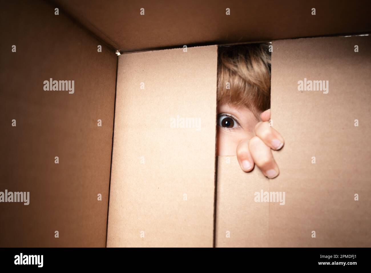Excited child boy looking into the box, shipping cardboard box. Close ...