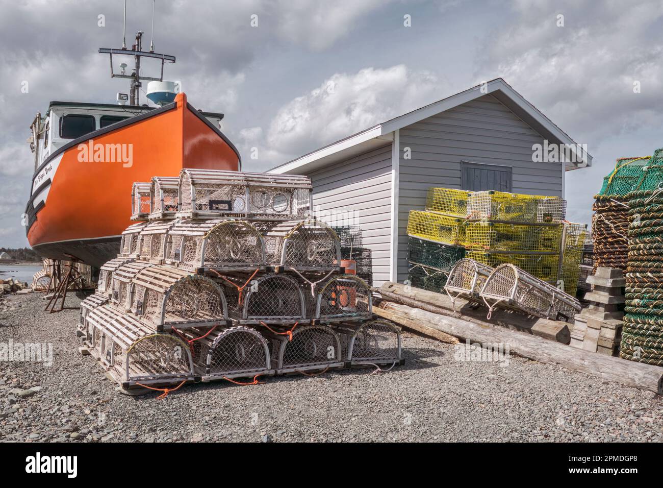 Orange fishing boat sits on shore for the winter awaiting the upcoming ...