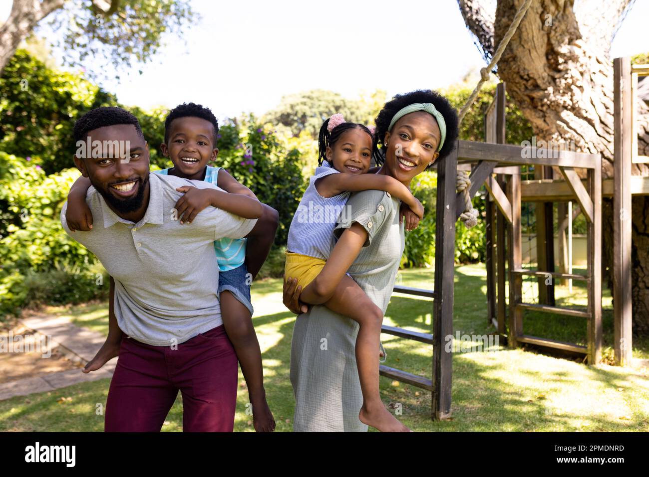Happy african american parents piggybacking son and daughter while ...