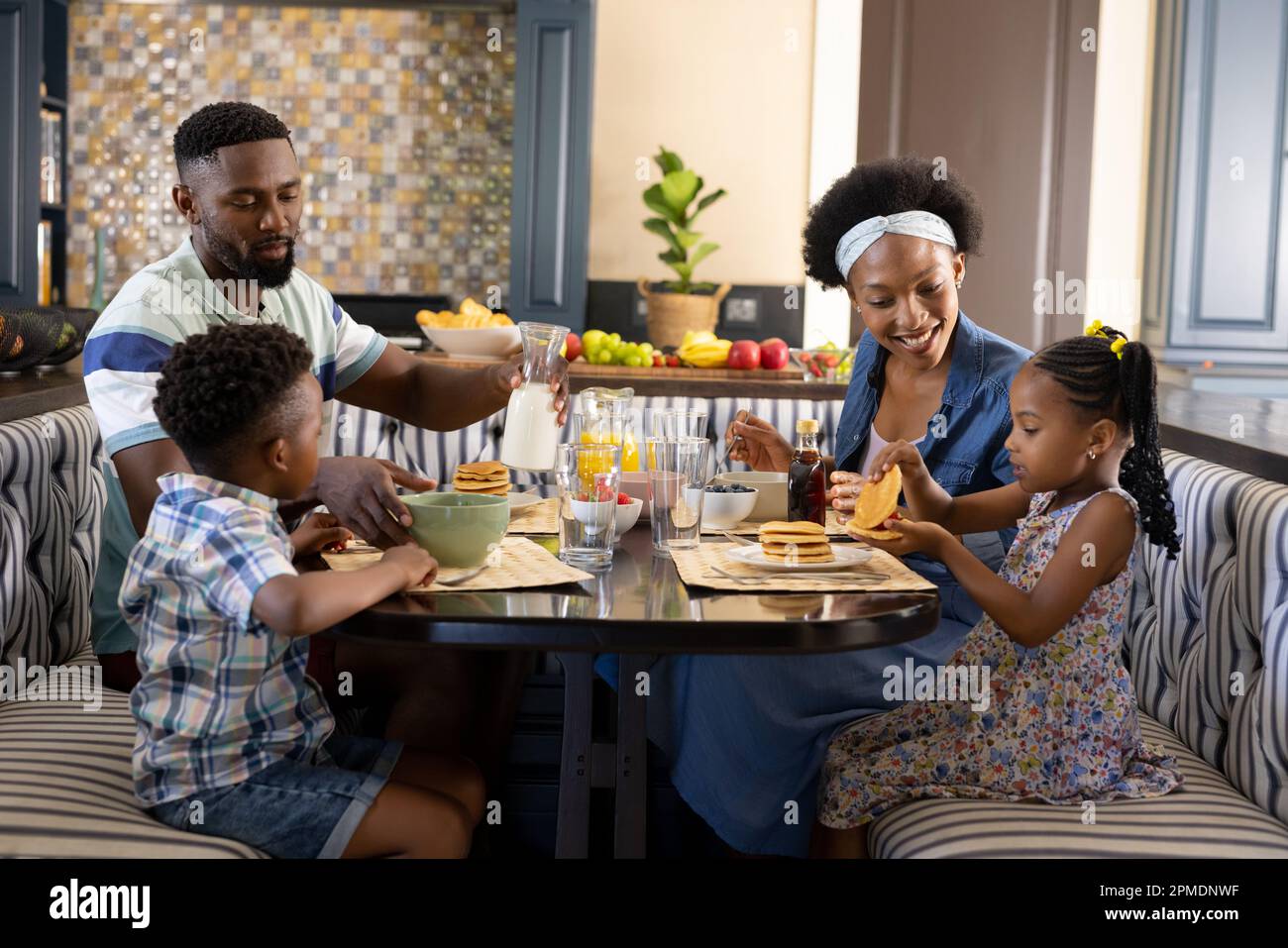 Happy african american parents and children having breakfast at dining table in morning, copy ...