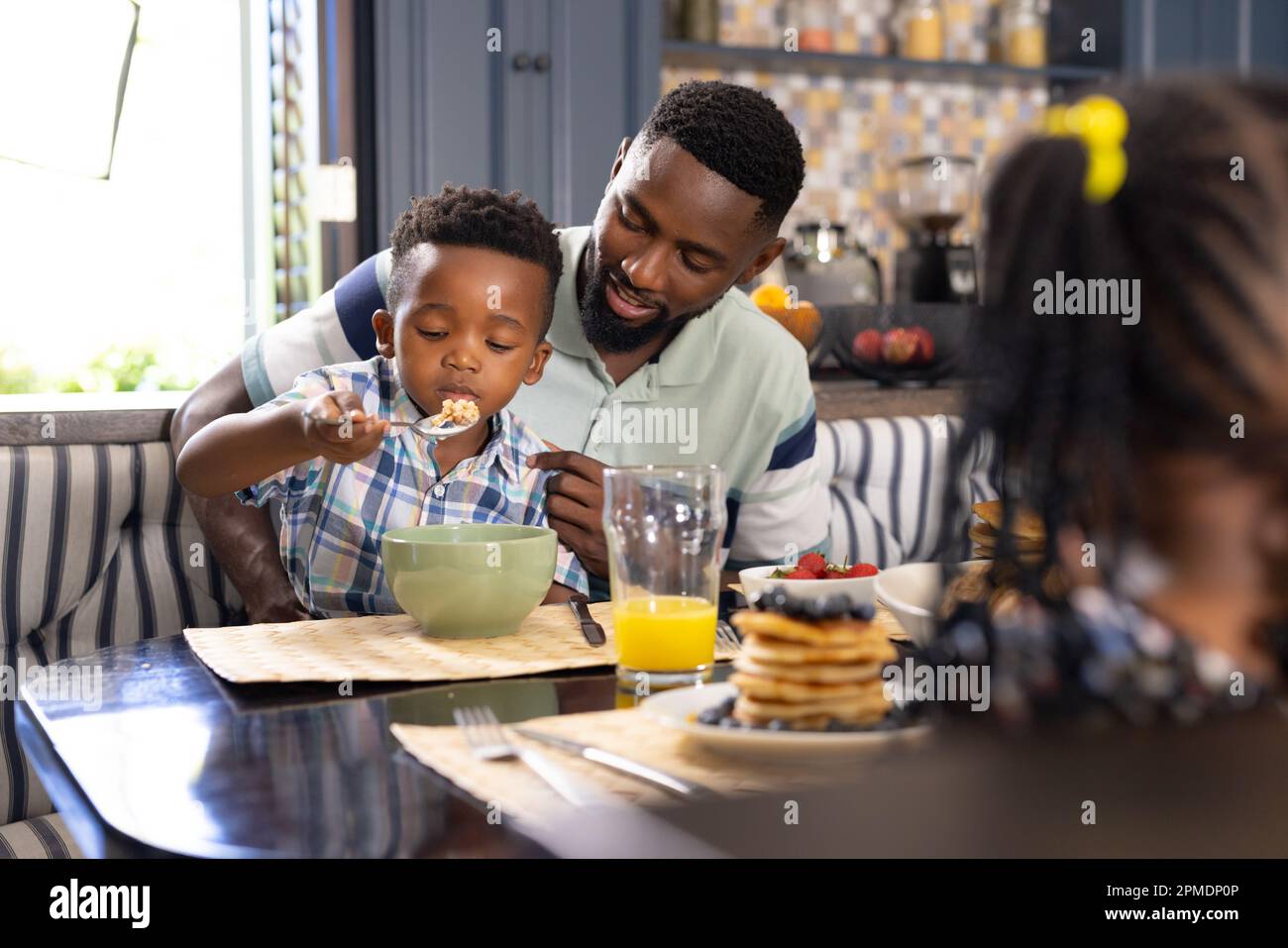 African american father looking at son eating breakfast cereals at ...