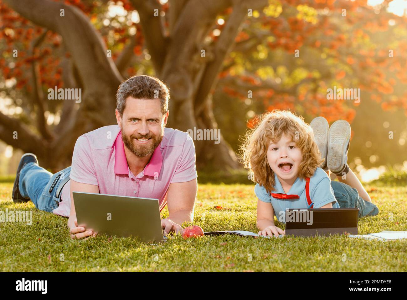 Outdoor education. Son with father watching lesson on laptop outdoors ...
