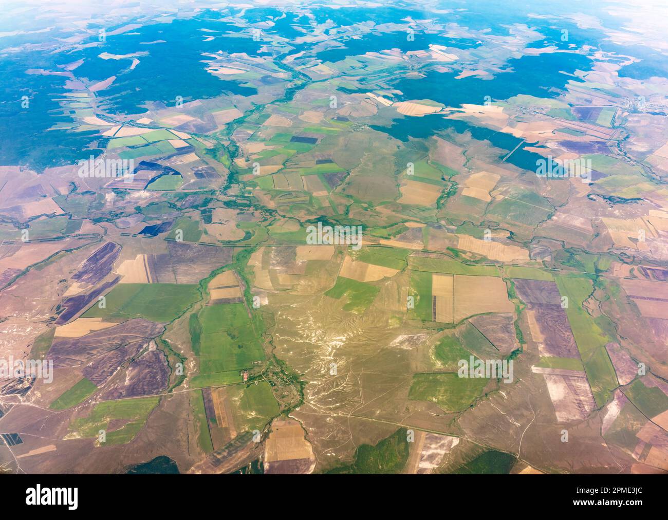 Aerial view from airplane window above green ground. View from the ...