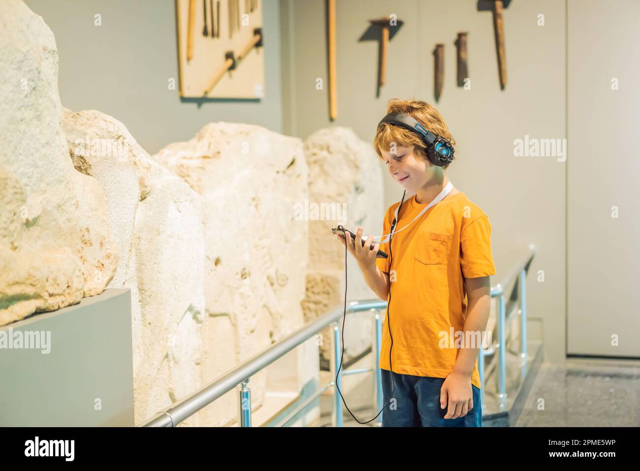 Boy looking at sculptures and listening to audio guide at museum ...