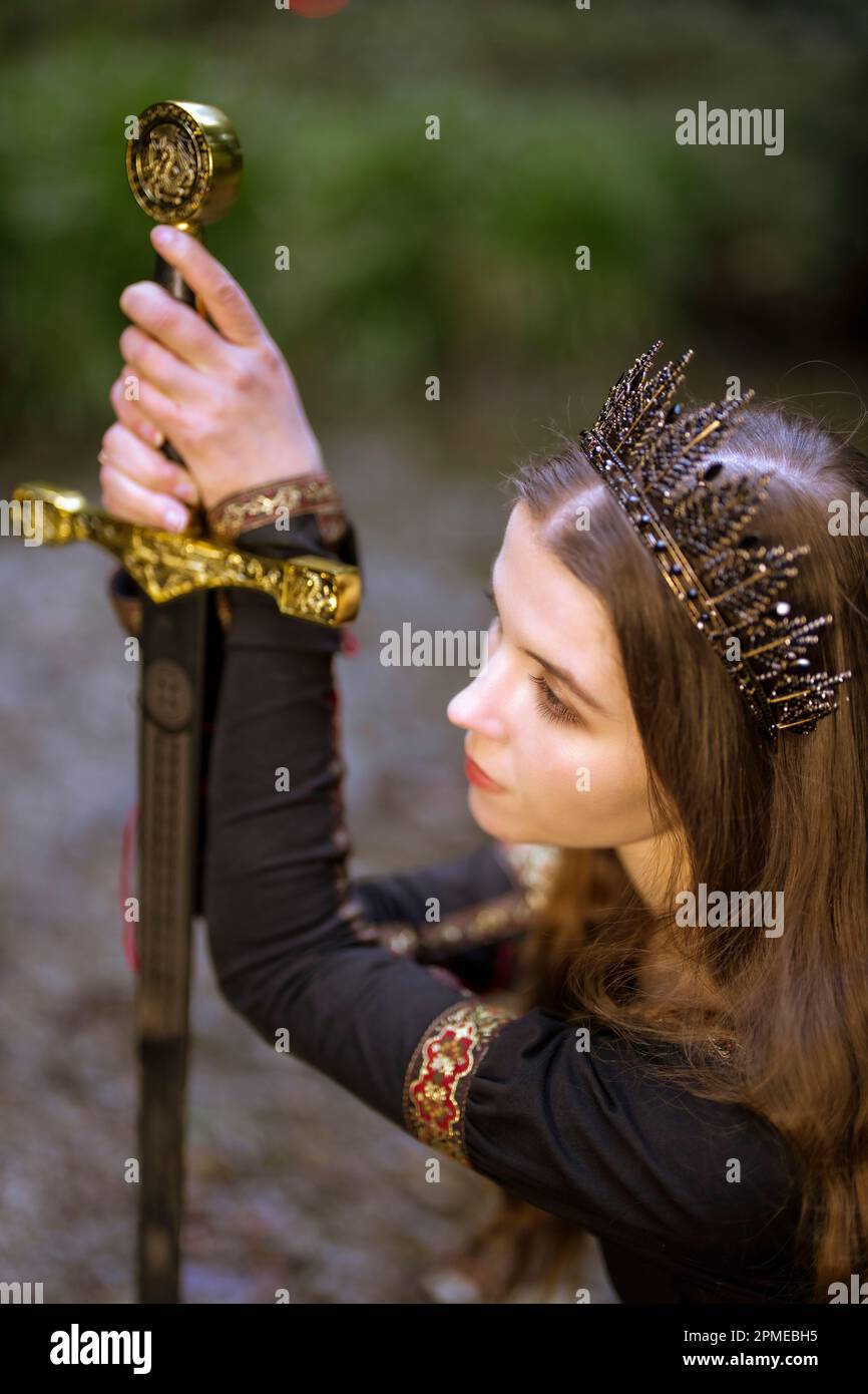 Young Woman Kneeling in Fairytale Queen Costume Holding Broadsword ...