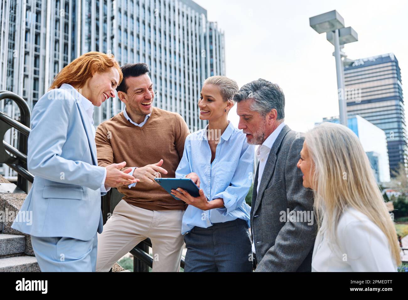 Relaxed group of business people using a tablet outdoors Stock Photo ...