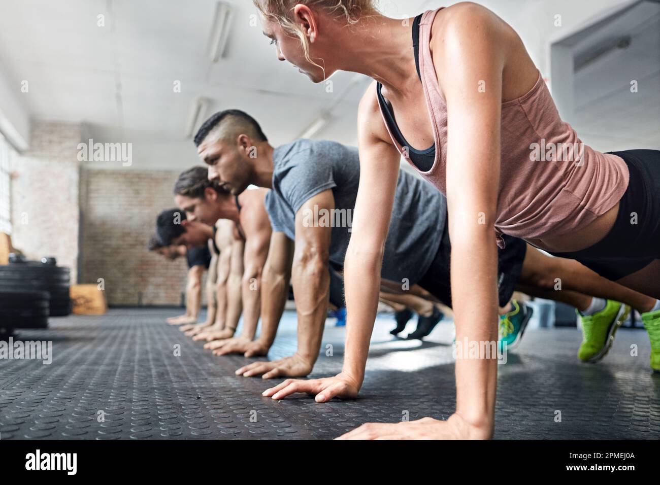 Push yourself. a group of people doing push ups in a gym Stock Photo ...