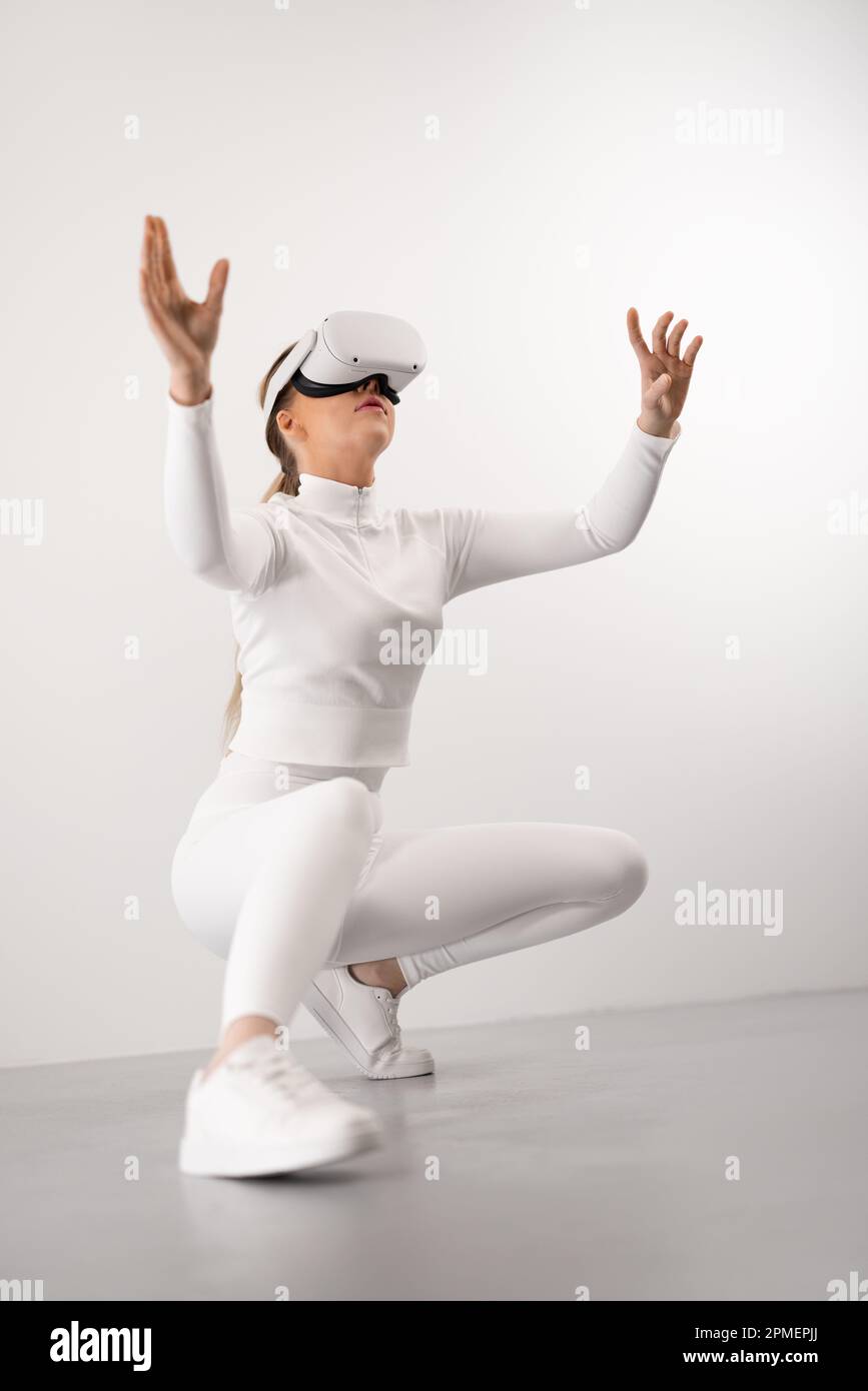 Futuristic and beautiful looking woman sitting squat down wearing VR ...
