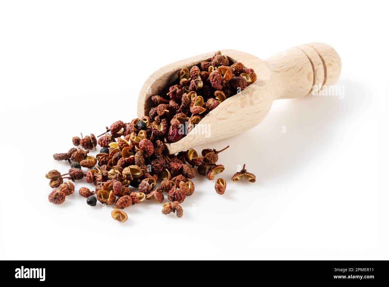 Scoop of sichuan pepper and wood set against a white background ...