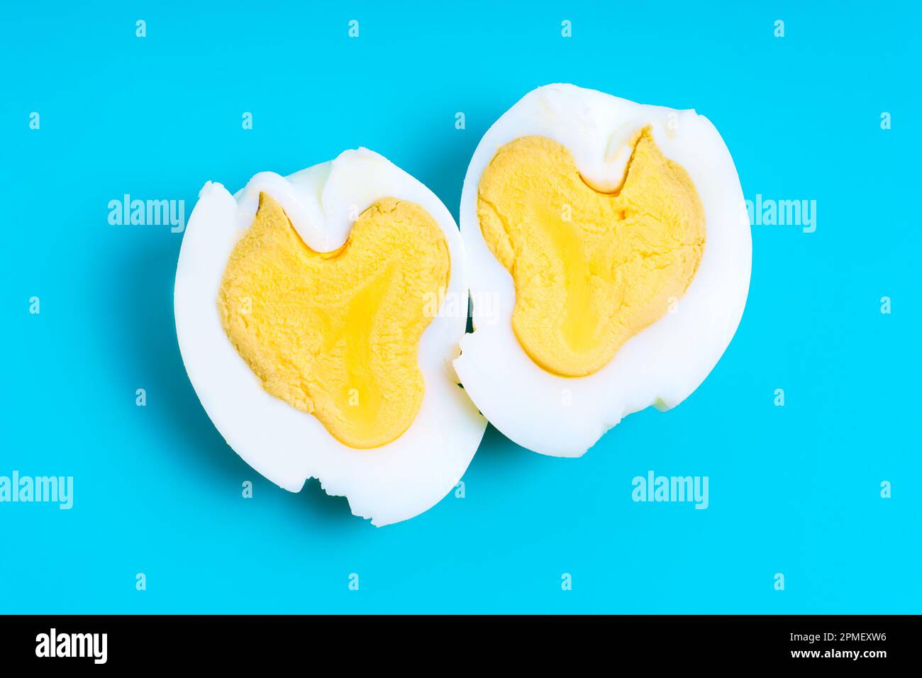 Two heart-shaped halves of a boiled egg isolated on blue background ...