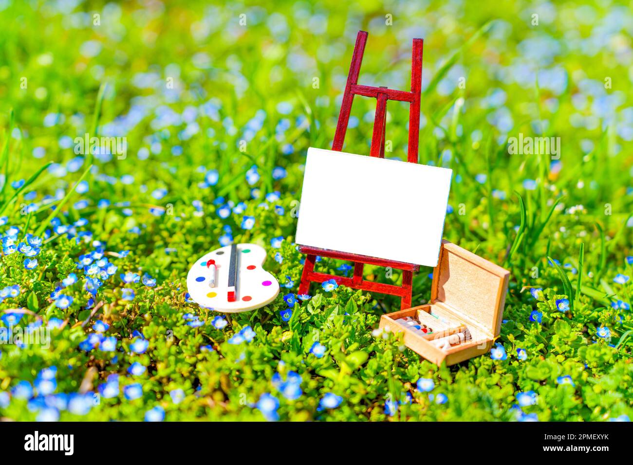 Tiny canvas on a small stand, miniature palette and wooden box with ...