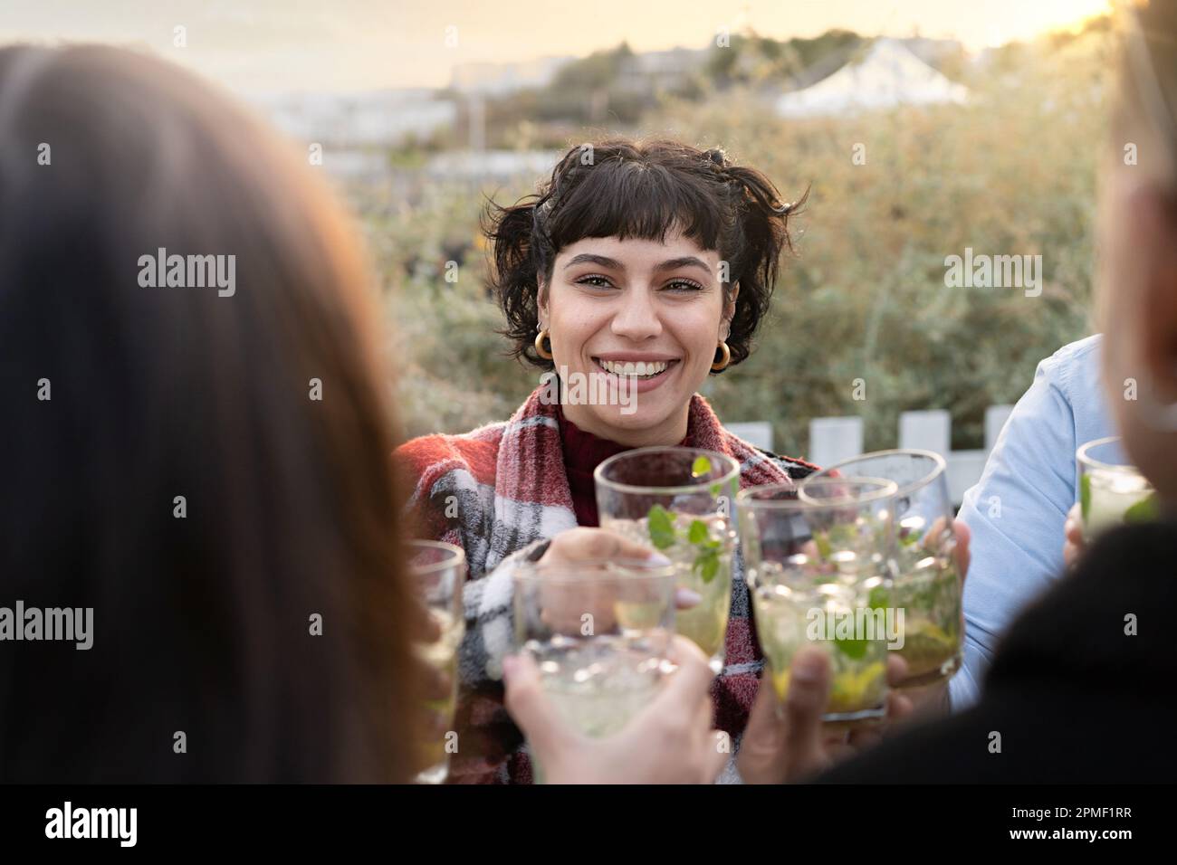 A group of friends toasting with fresh cocktails at an outdoor bar. A ...