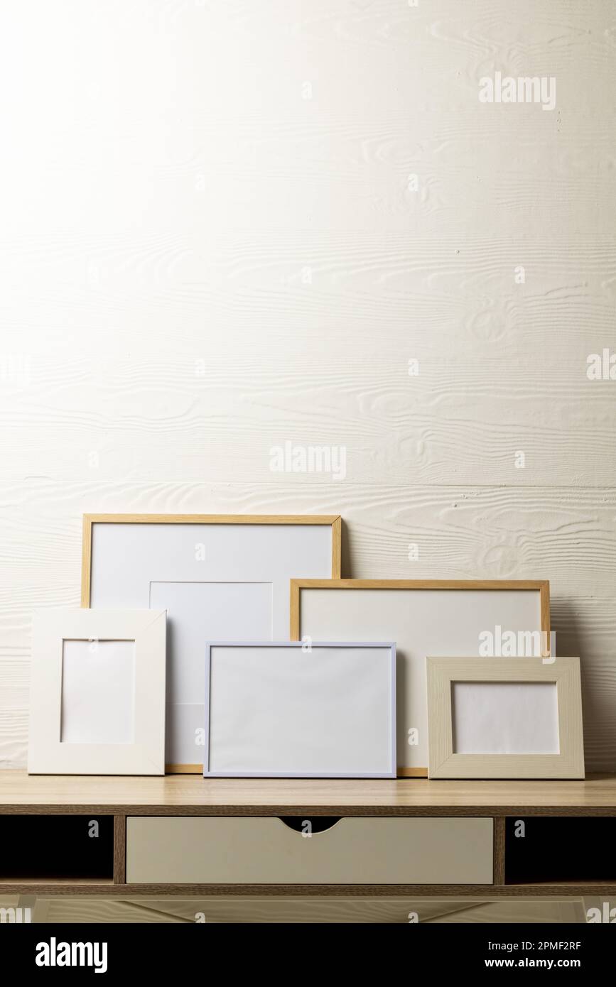 Vertical of five various empty frames with copy space on table against ...