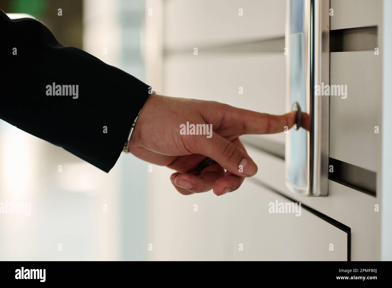 Close-up of businessman pushing button to use elevator in office ...
