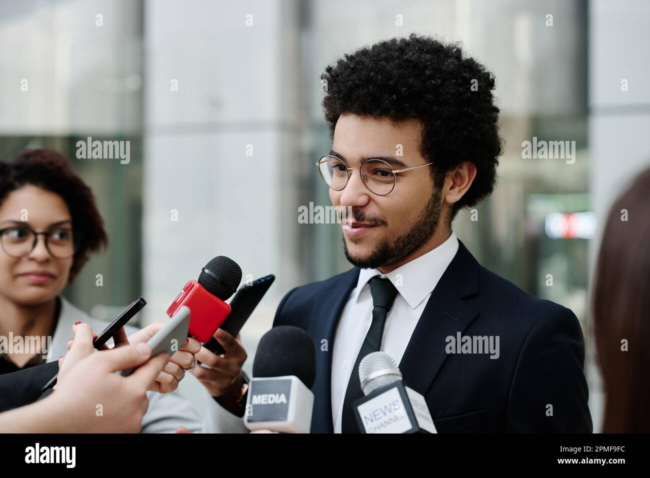 Young businessman in suit giving an interview to reporters during ...