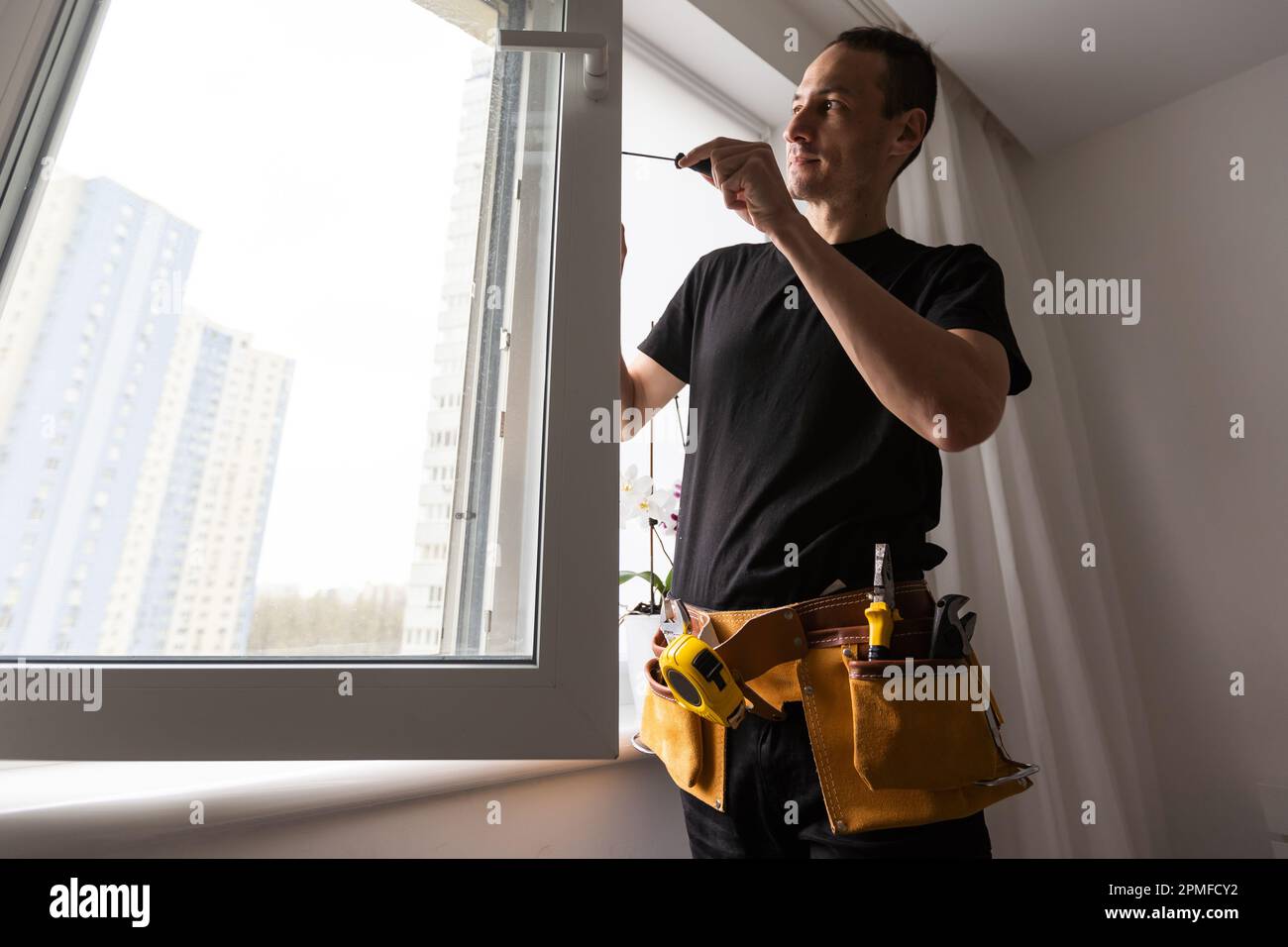 Worker adjusting installed window with screwdriver indoors, closeup ...