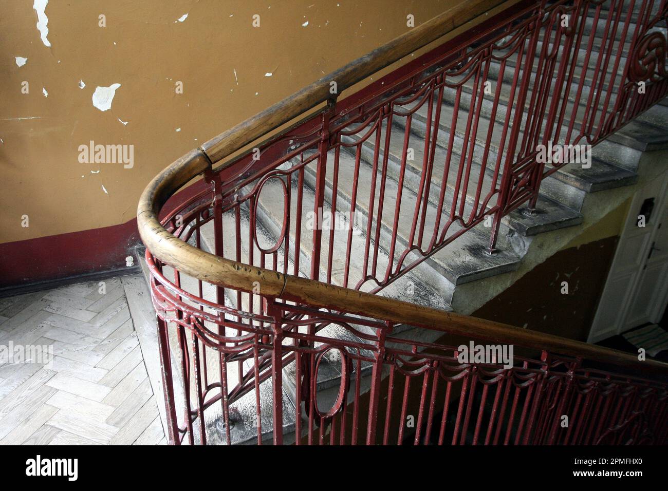 Old staircase in tenement house, wrought iron railing covered with wood ...