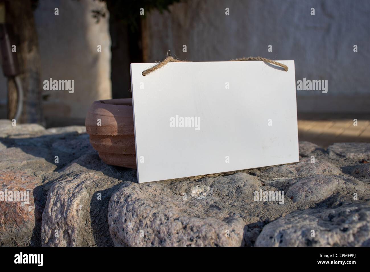 traditional stone wall and white hanging picture sign with empty free ...