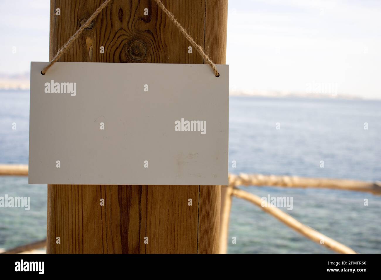 vertical wooden post with the blue sea in the background and a white ...