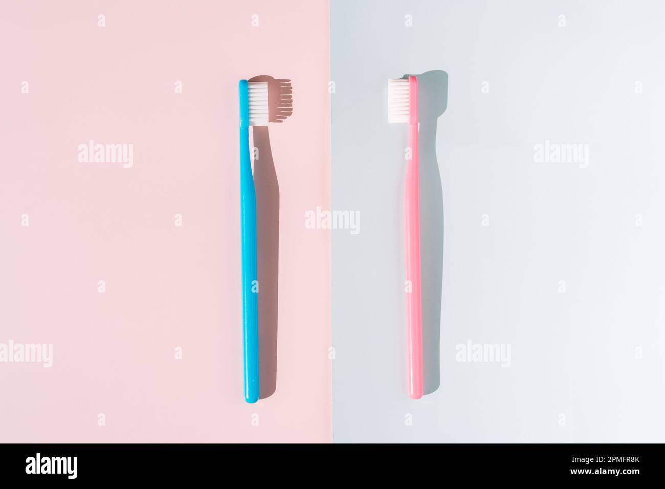 Blue and pink toothbrush on pink and blue background under hard light ...