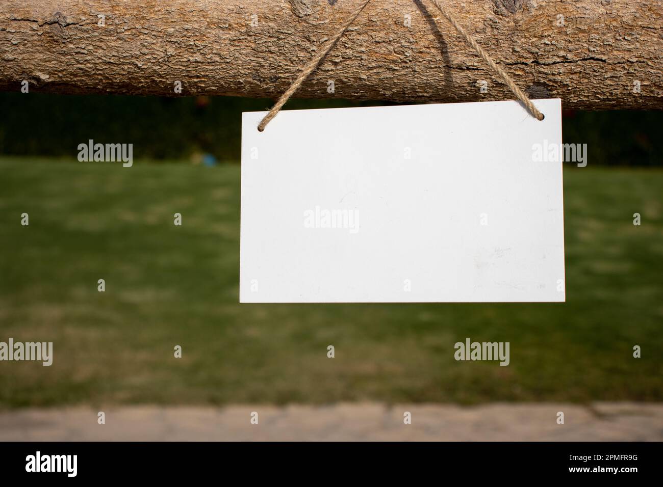 white hanging picture sign hanging from a rustic wood with green grass ...
