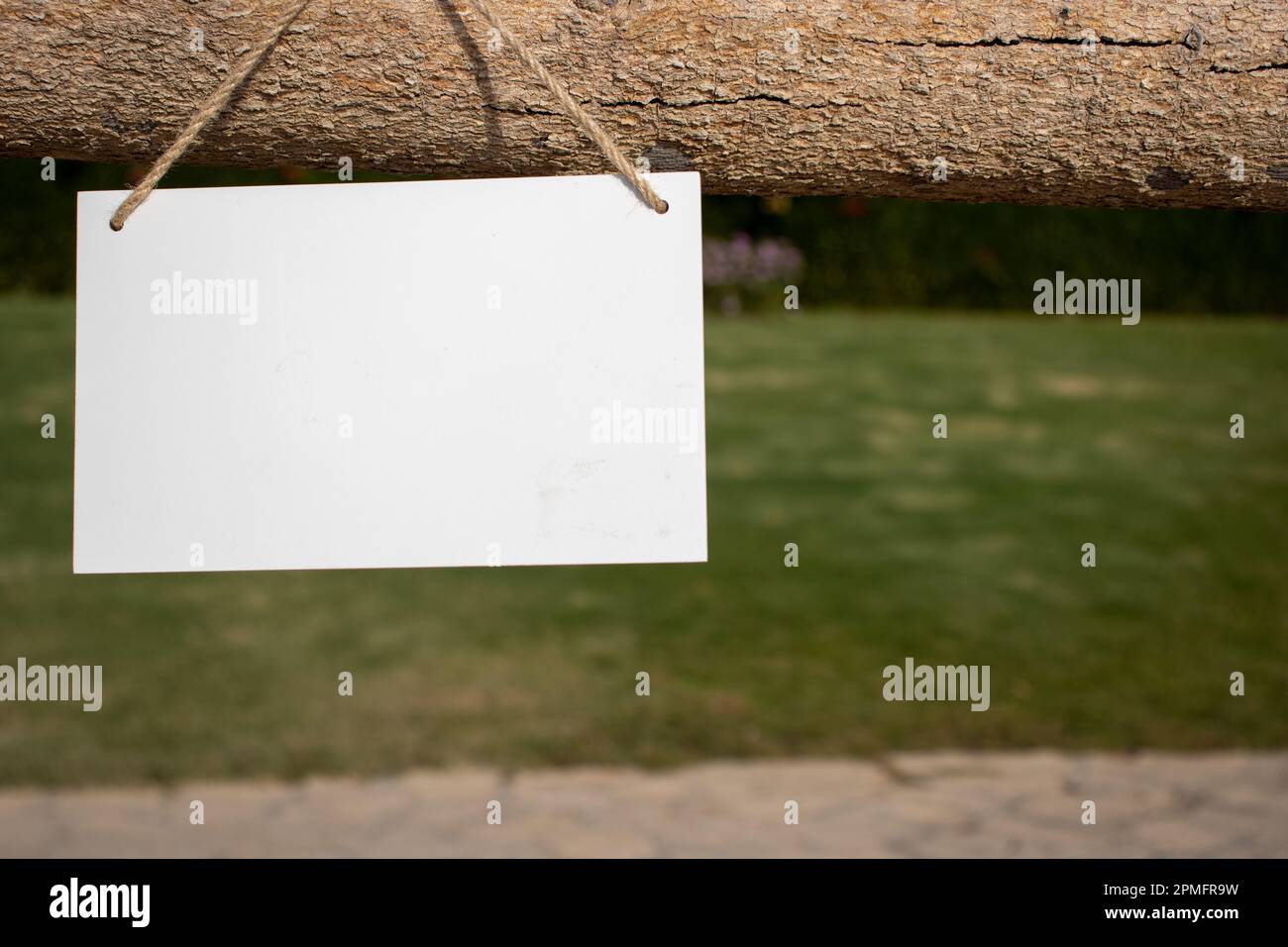 white hanging picture sign hanging from a rustic wood with green grass ...
