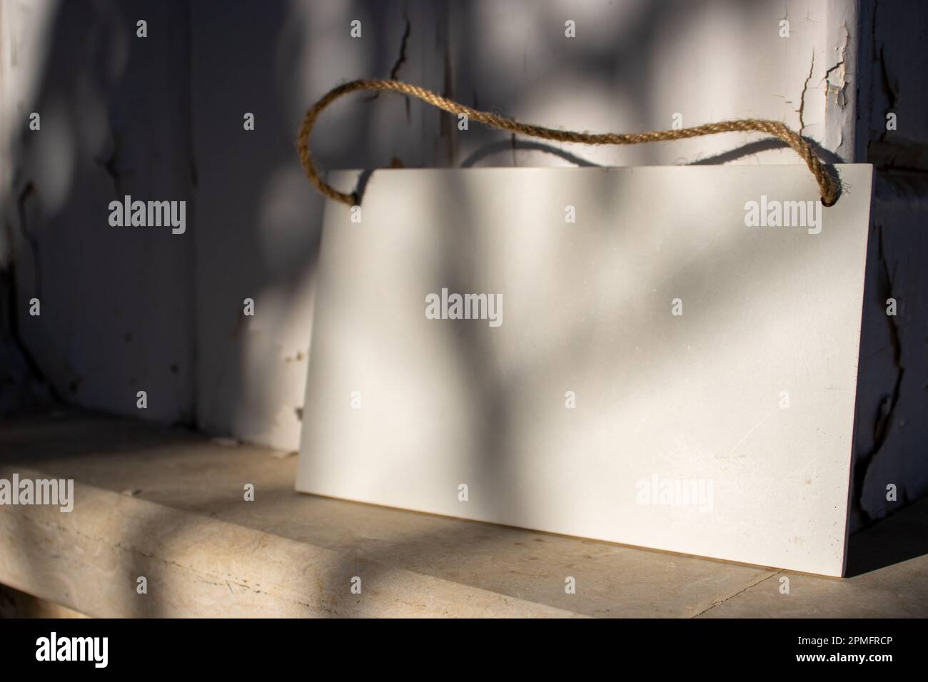 white hanging picture sign in shadow with empty free space for template ...