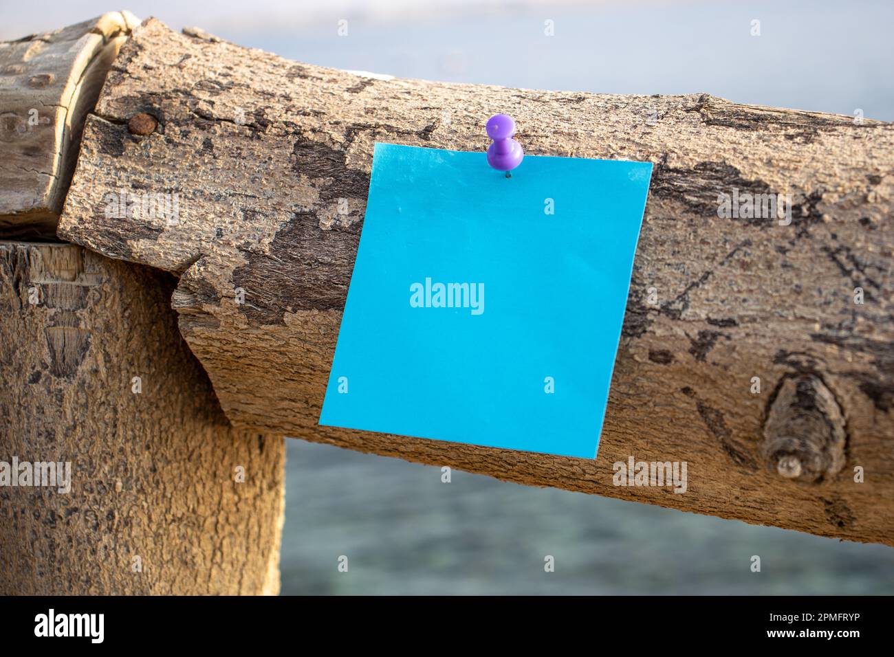 wooden fence post and purple map pin and blue square paper note with ...