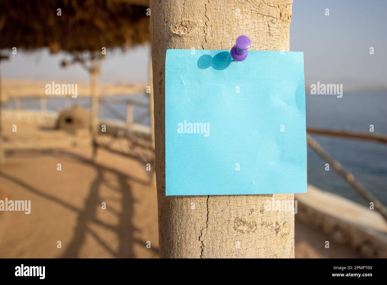 wooden round post with the sea behind purple map pin and blue square ...