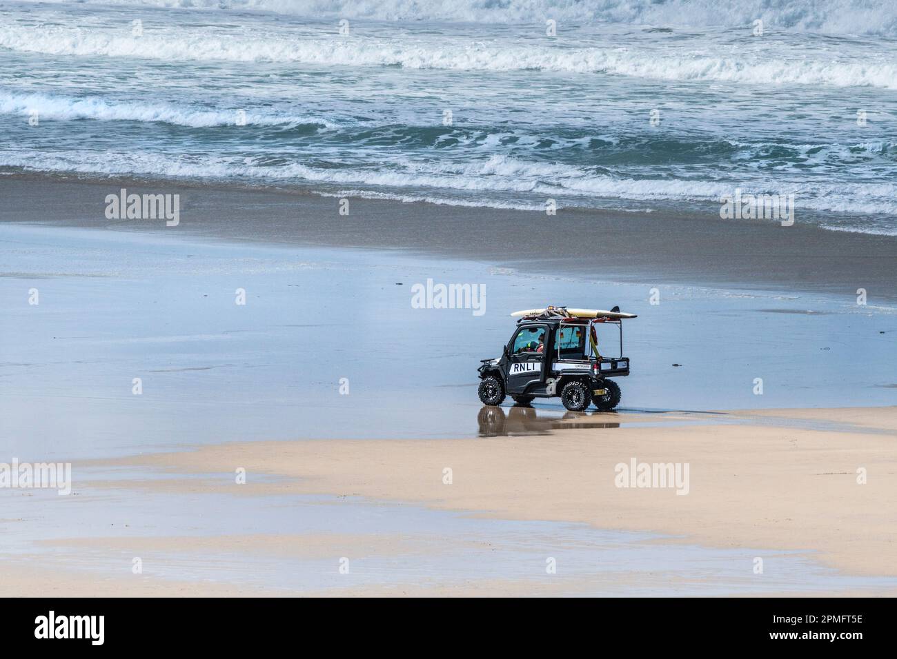 A small RNLI emergency response vehicle patrolling Fistral Beach in ...