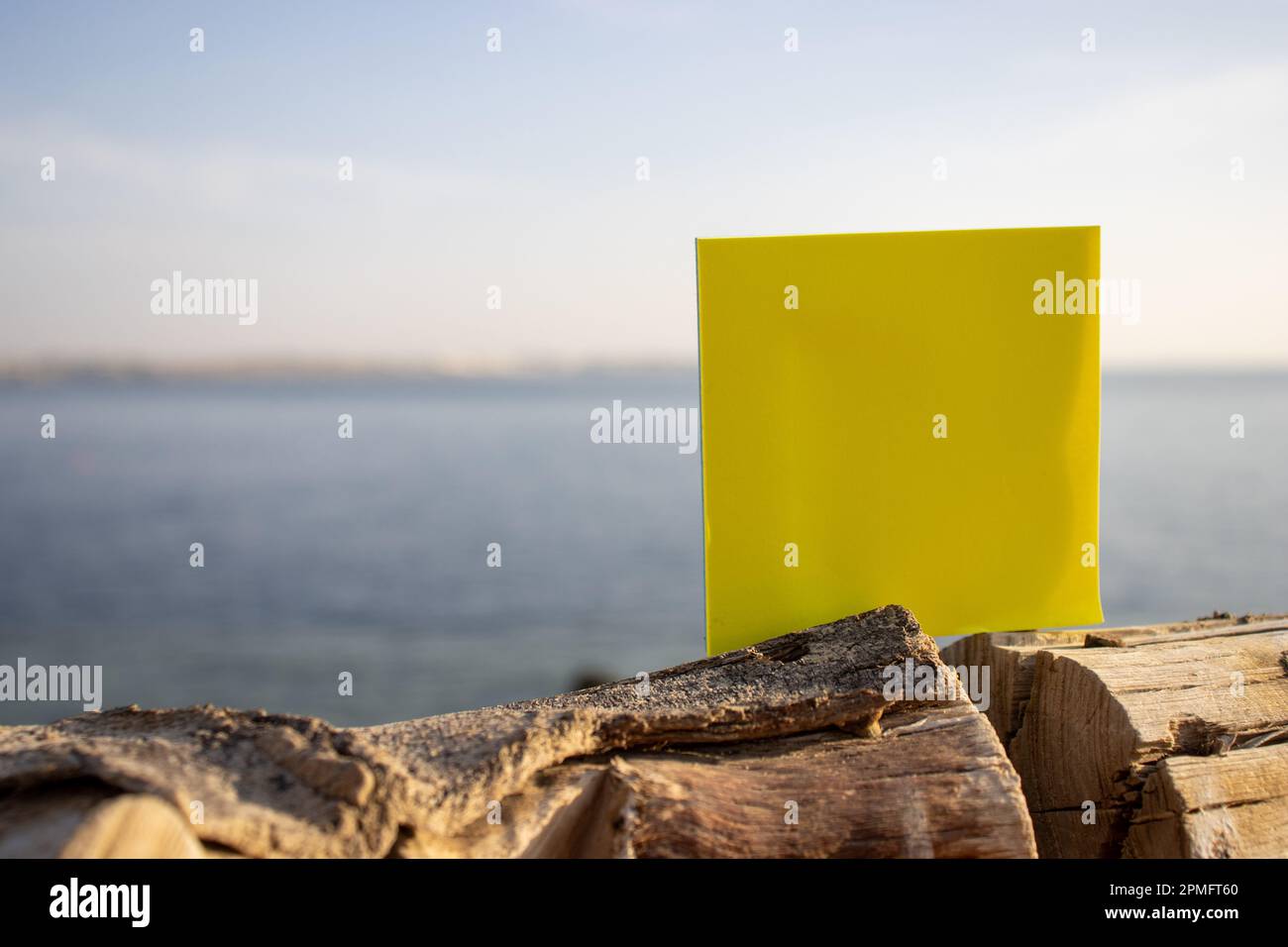 yellow square paper note resting in the crack of a round wooden fence ...