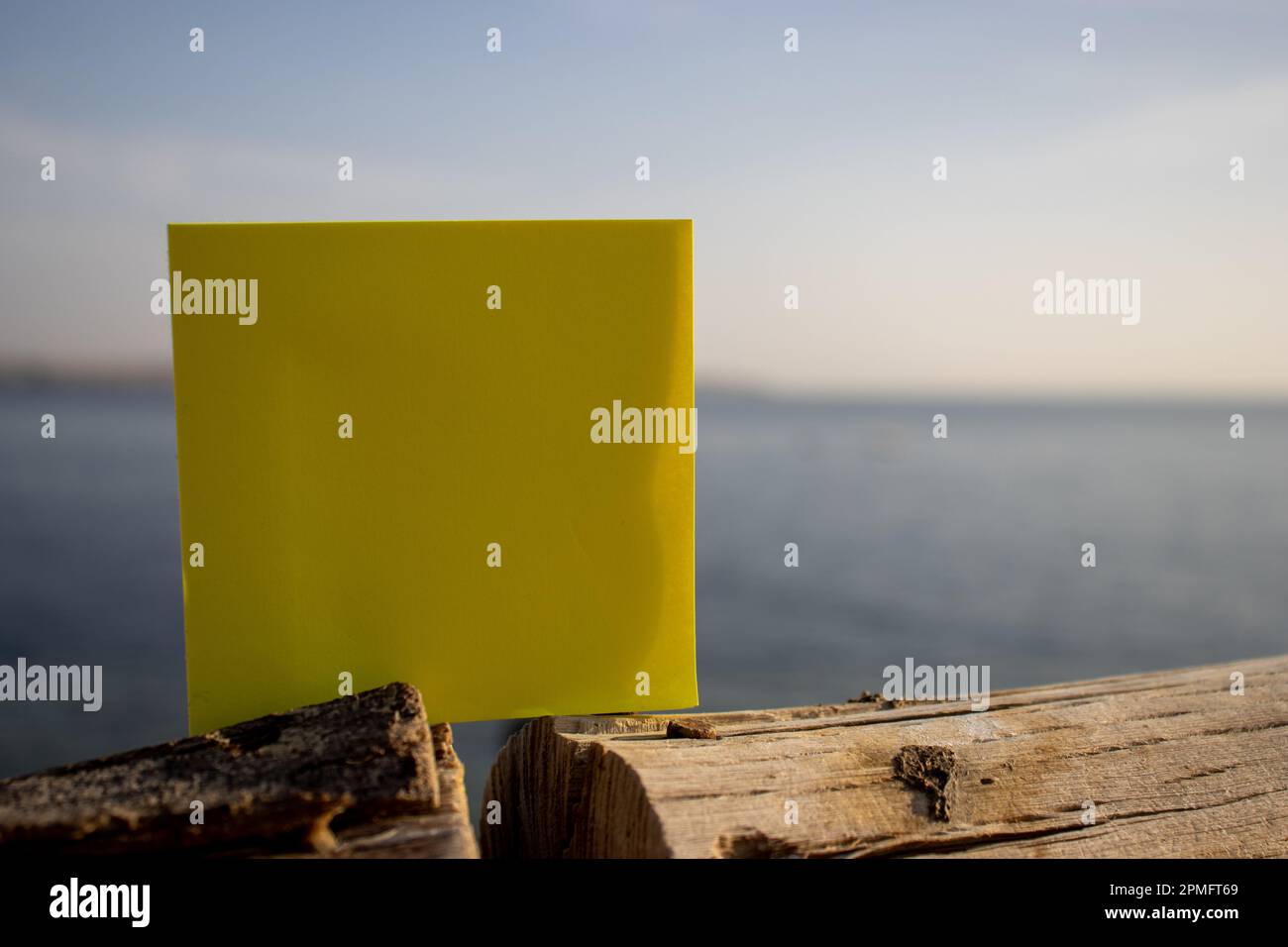 yellow square paper note resting in the crack of a round wooden fence ...