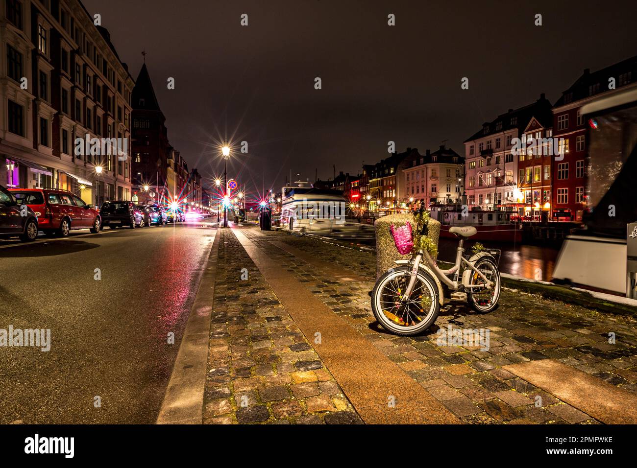 City bike parked near water canal, long exposure, night lights of ...