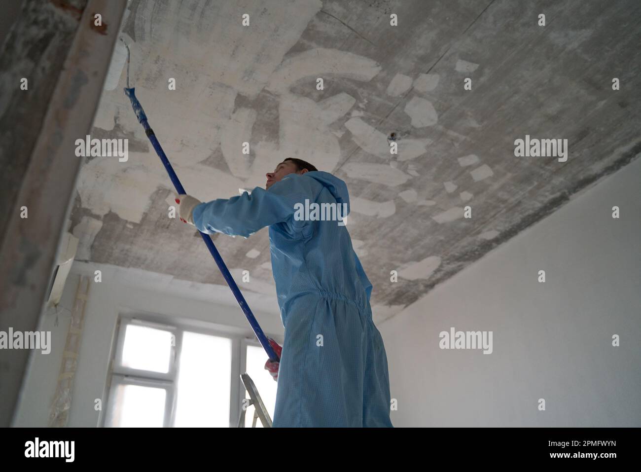 Man paints the ceiling with a roller. Concept of home makeover and ...