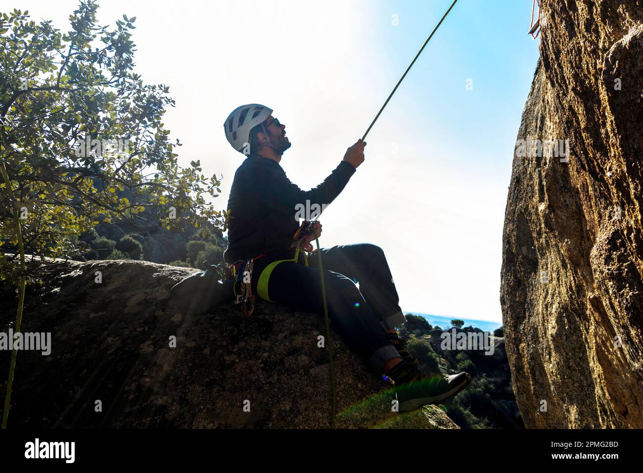 Rock climber sitting on a ledge while supporting his teammate in ...