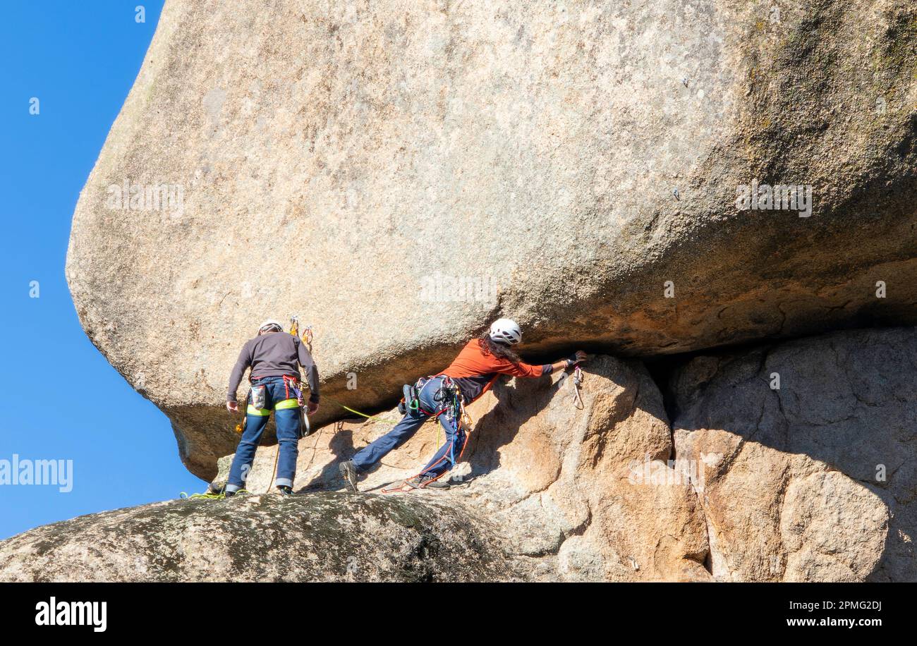 two young adults working together to climb a granite wall. Rock ...