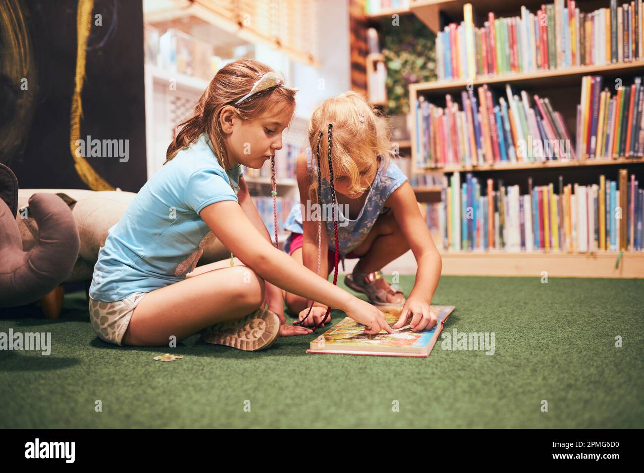 Two elementary schoolgirls solving puzzles and riddles in school ...