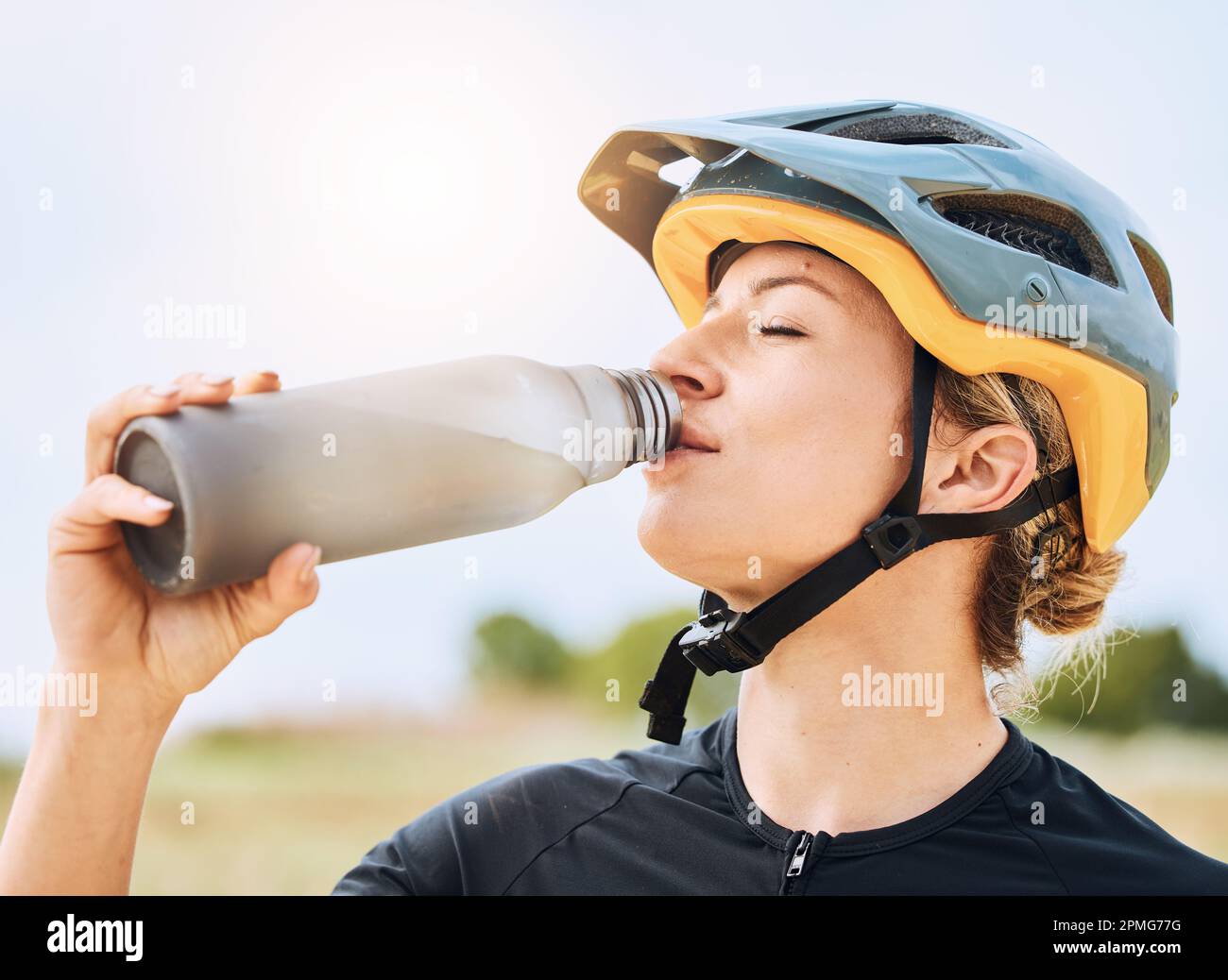 Woman drinking water, bottle and cycling with exercise outdoor, helmet ...