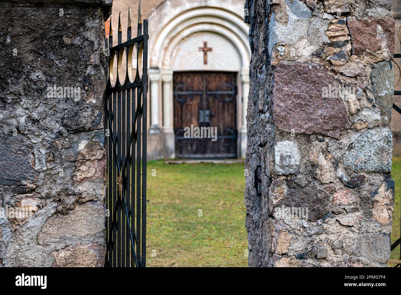 A fragment of a church fence with an open iron gate in the background ...