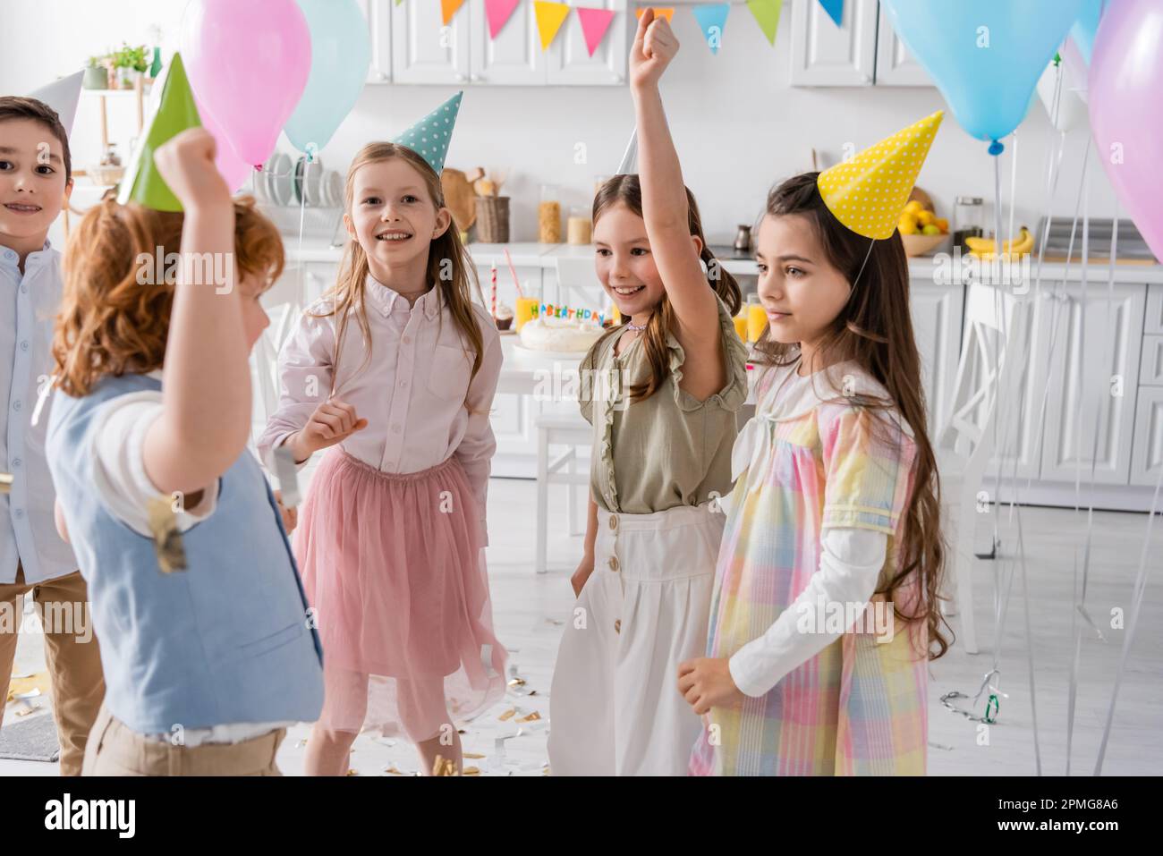 group of happy children in party caps dancing during birthday ...