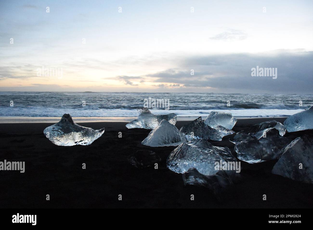 Broken ice cubes scattered on a sandy beach shoreline Stock Photo - Alamy