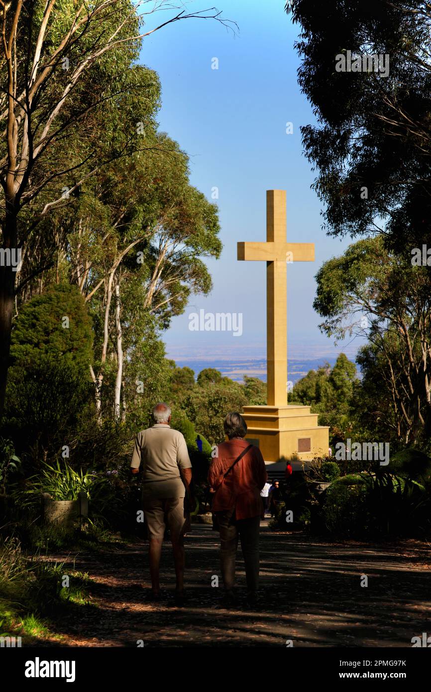 Two people walking through a park, heading towards a Christian cross ...