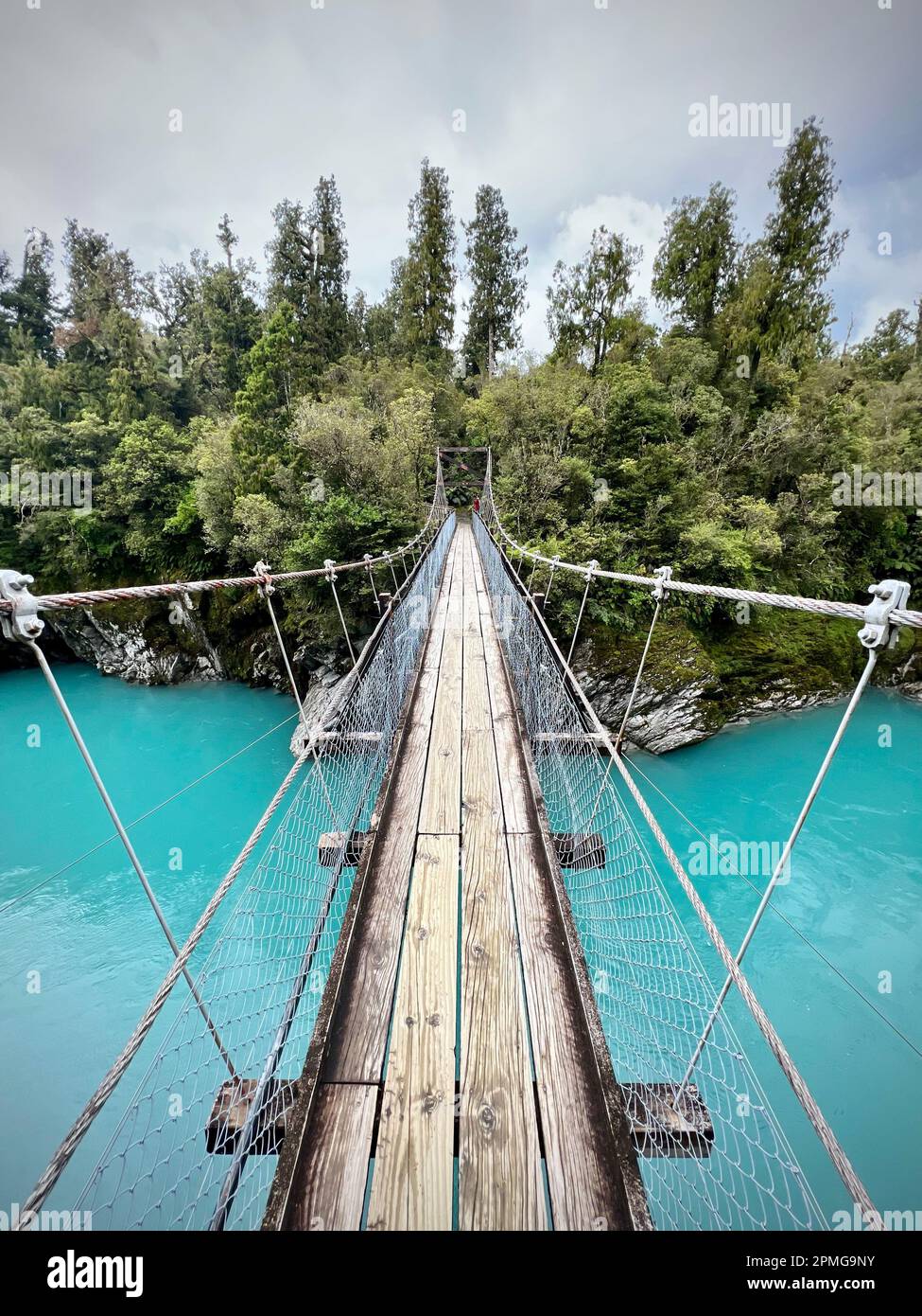 A stunning suspension bridge arching over a vibrant blue river, with a ...