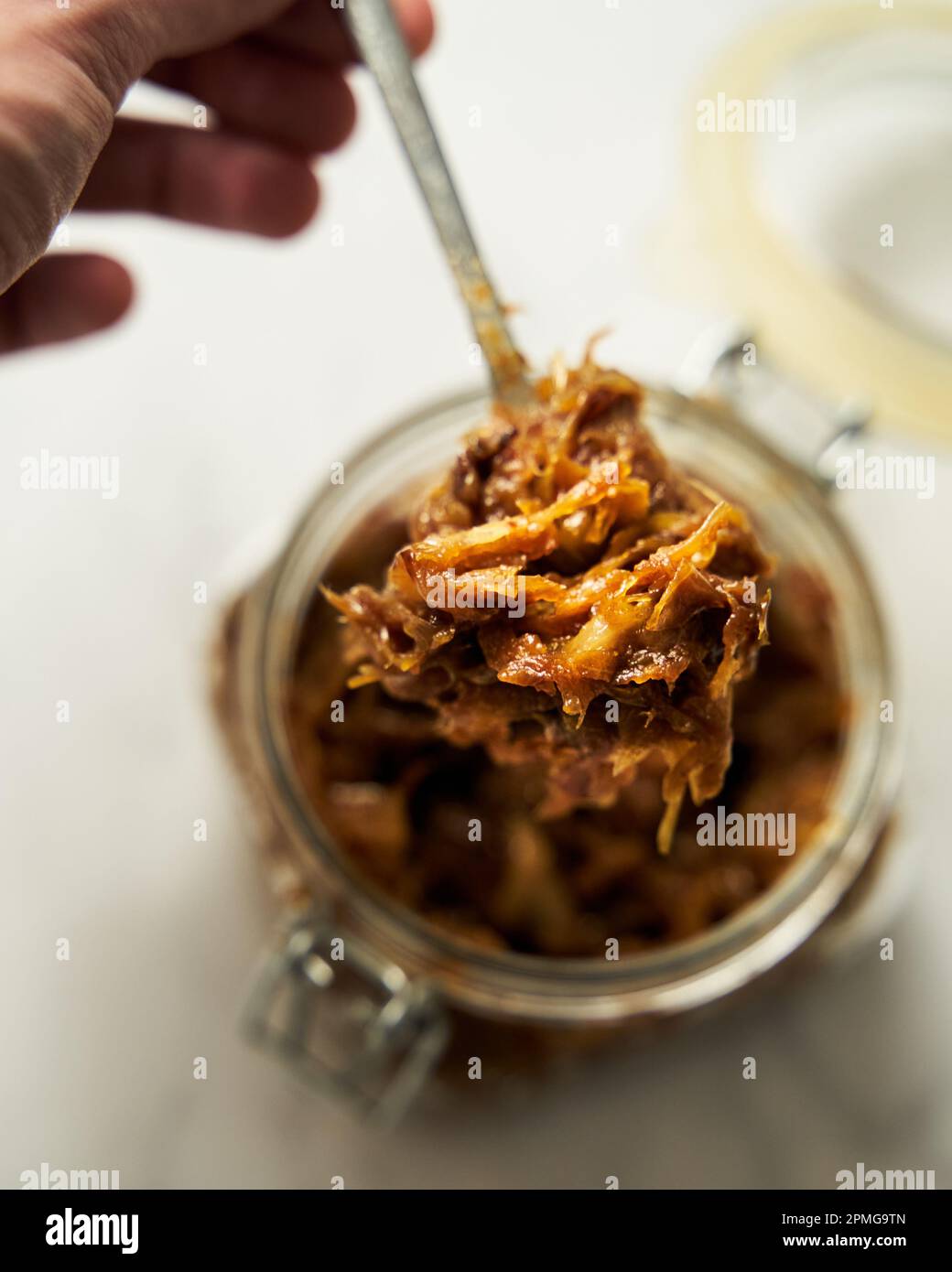 Homemade Caramelized onions in the jar. Man's Hand with spoon reaches ...