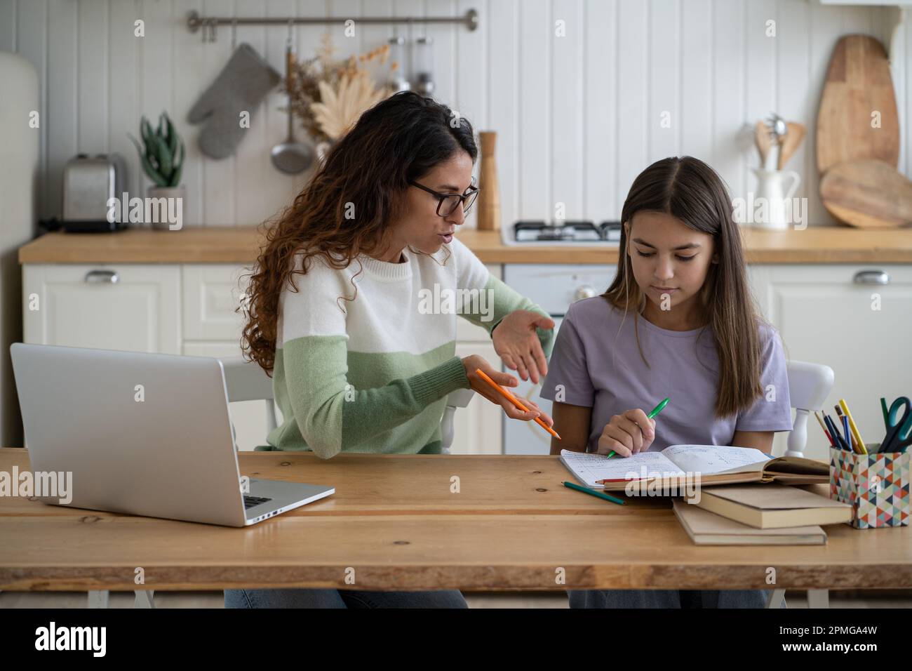 Indignant woman tutor with laptop helping teenage girl to prepare for ...