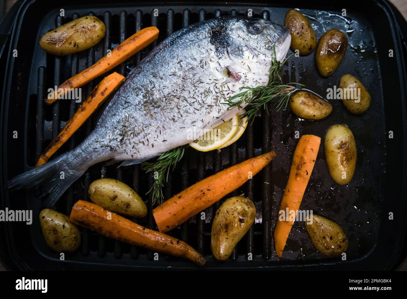 Sea fish with carrot and sweet potato on the grill. Top view Stock ...