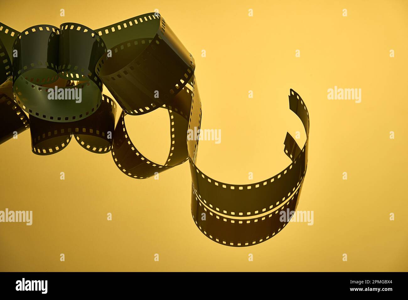 A close-up image of a motion picture film reel casting a reflection in ...