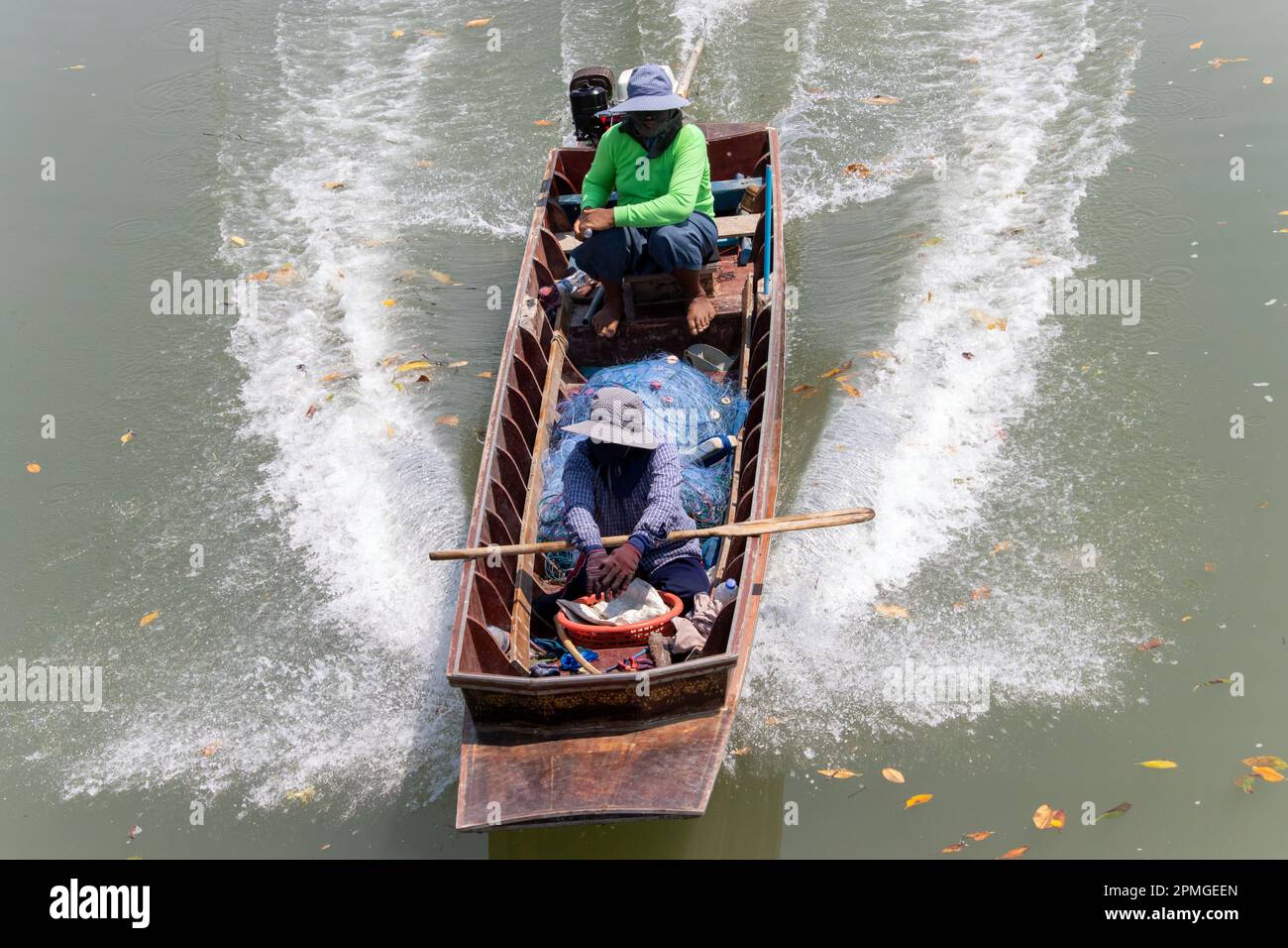 A couple rides a boat with fishing net in a water canal on the ...